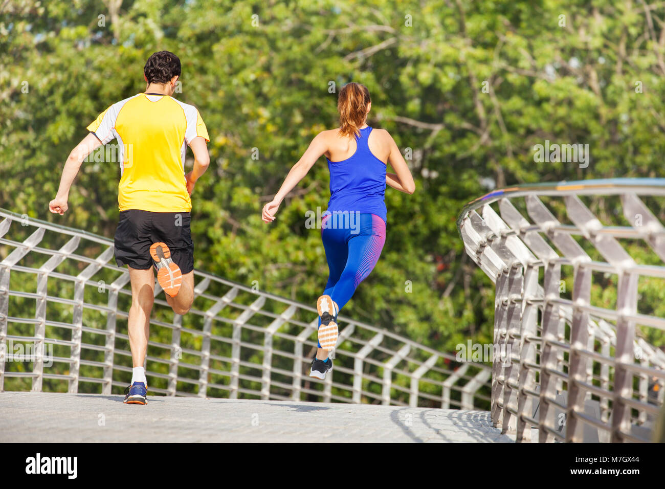 Back view portrait of active young couple in sportswear running at city ...