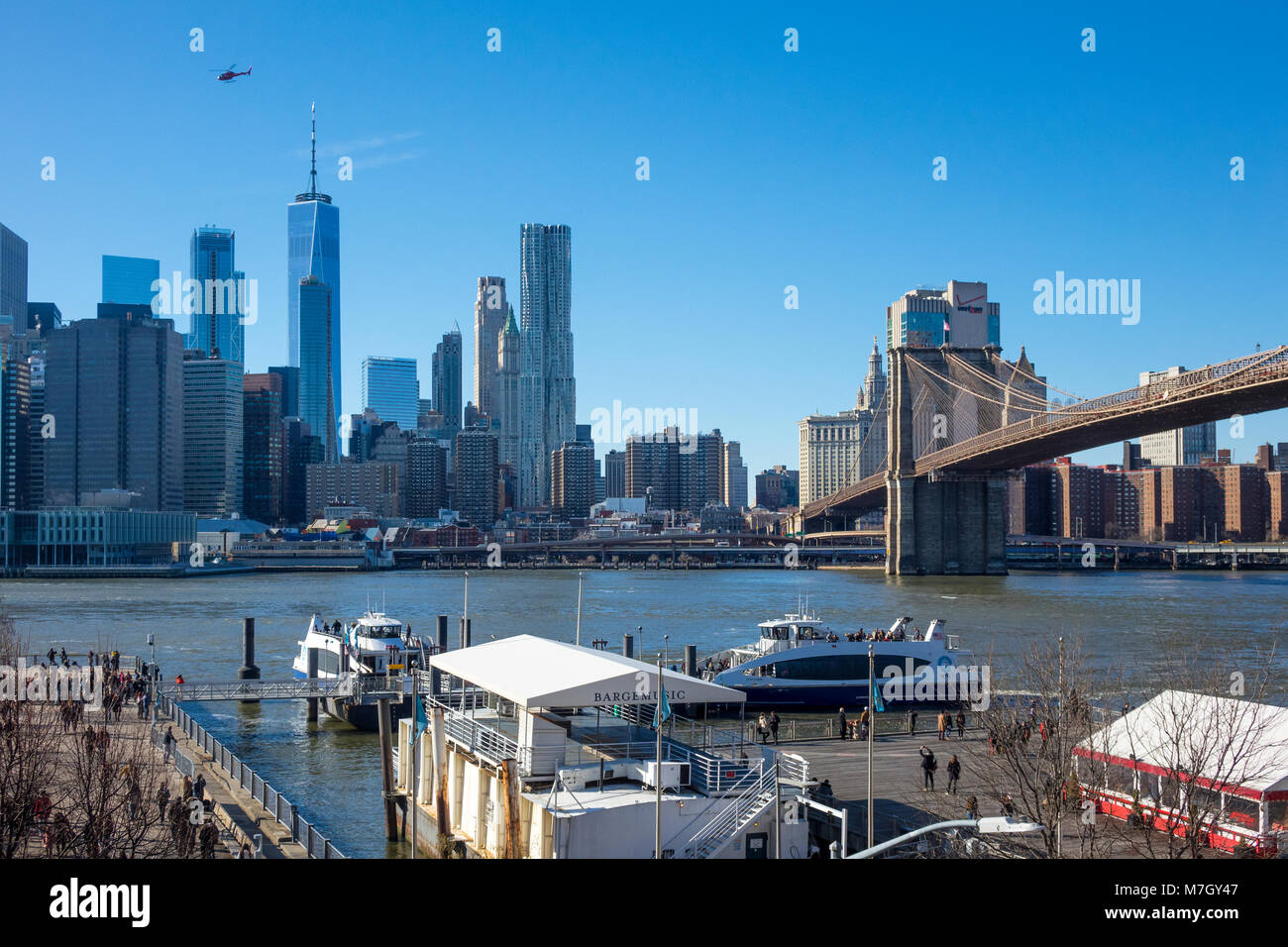 A small helicopter flying over the East River next to the Lower ...