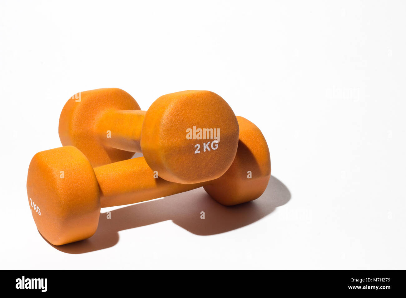 Orange dumbbell on white background close up Stock Photo - Alamy