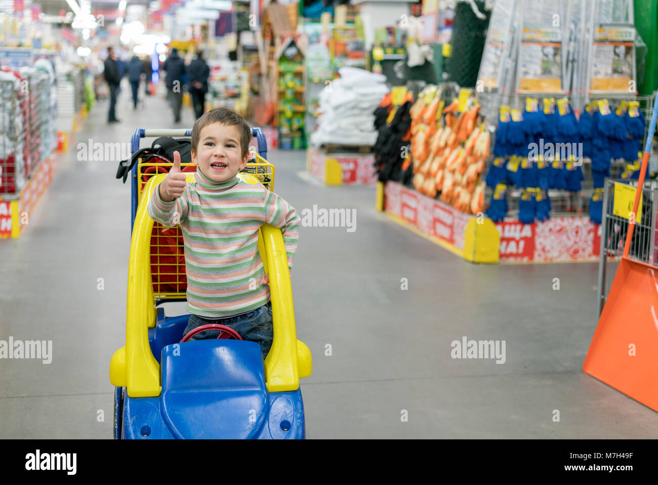 The boy 4 years leaned out of the children's cart in the building store ...