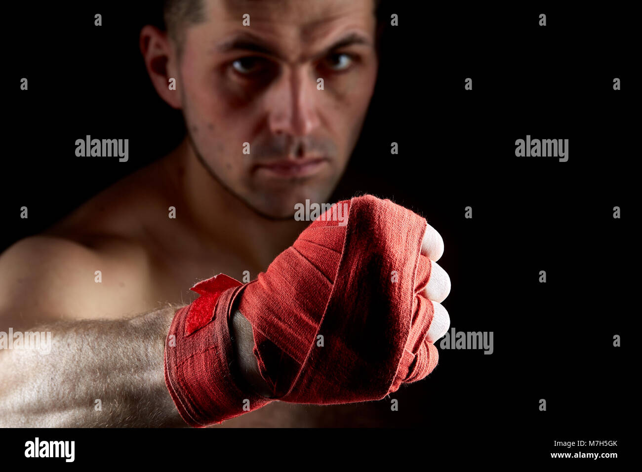 Close up low key portrait of a aggressive muscular fighter, getting ...