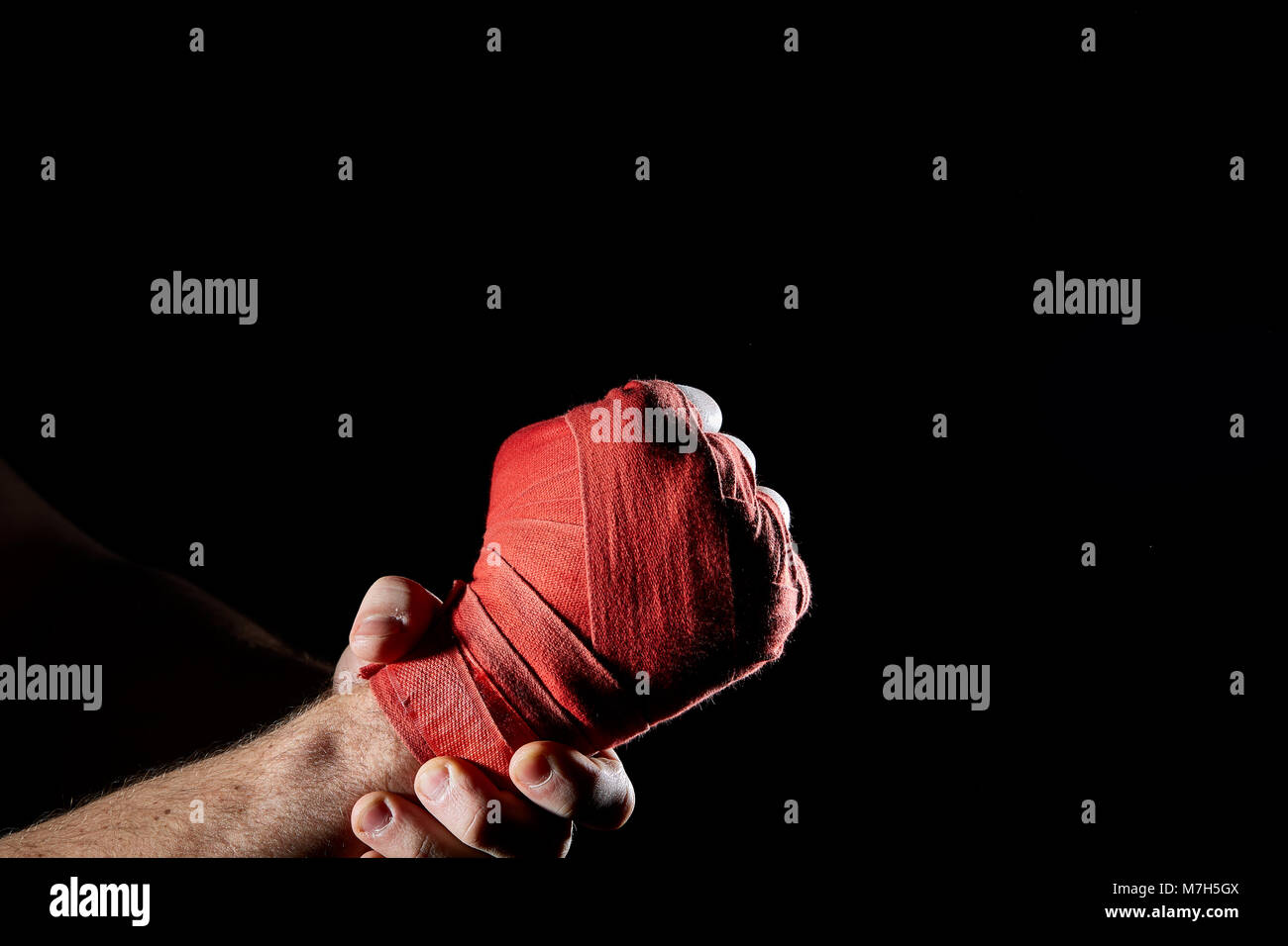 A boxer's red elastic bandage on his hand isolated over dark blurred ...