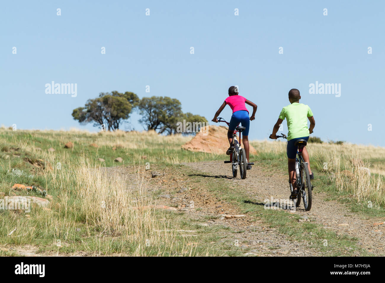 African children riding a bike on a dirt road in rural South Africa ...
