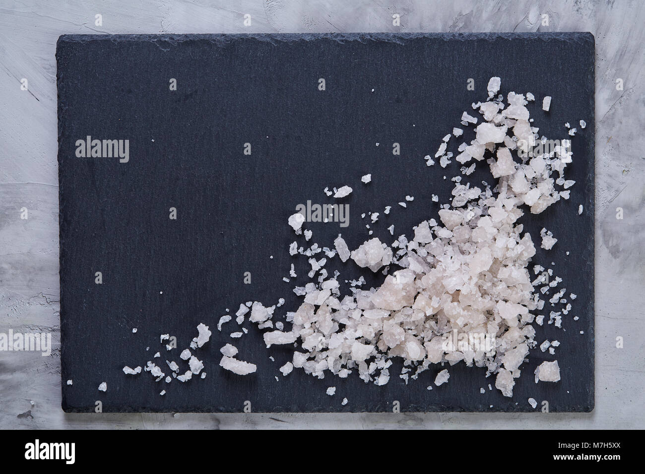 Pile of salt crystals isolated on the dark board over white textured ...