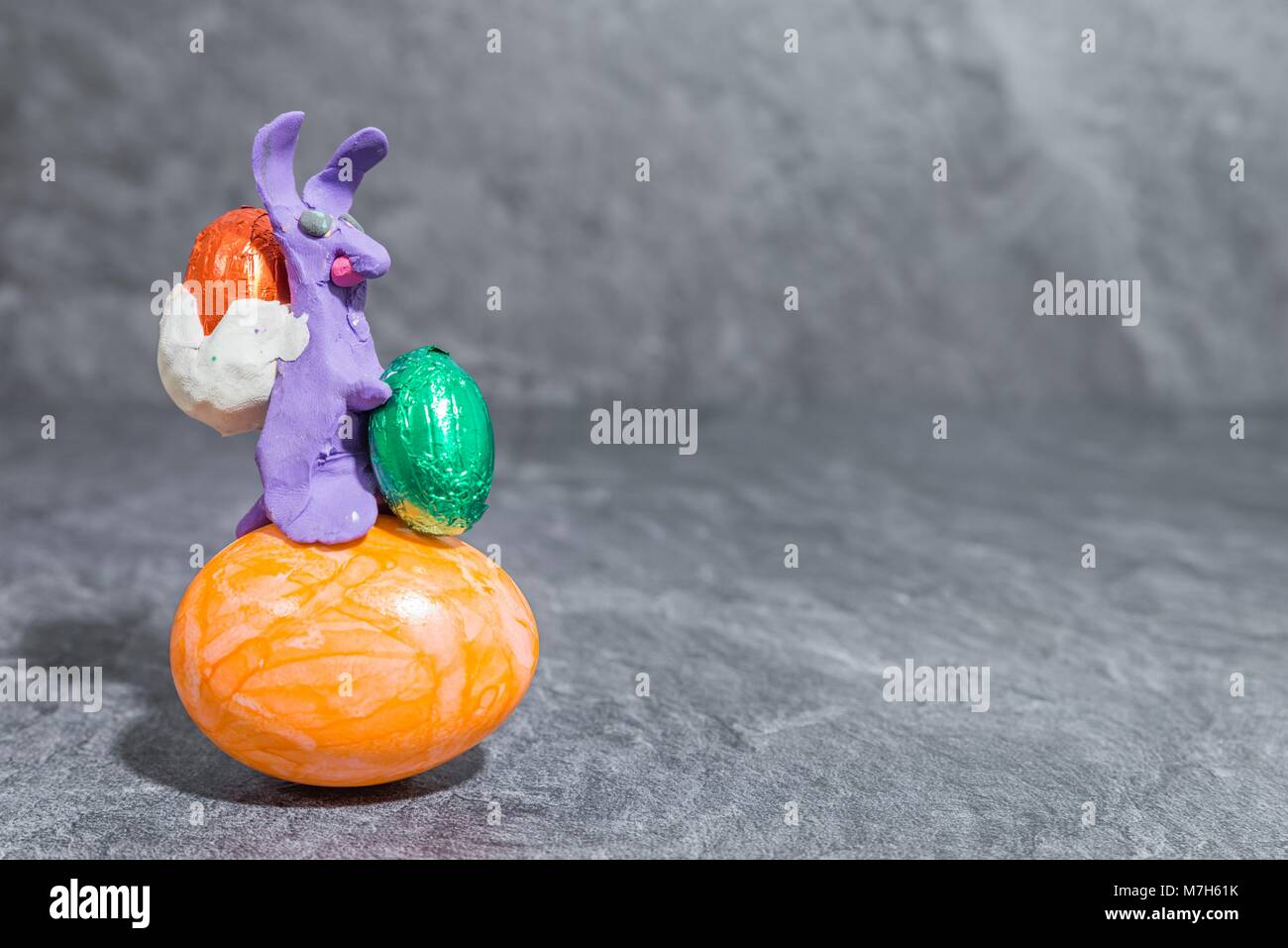 Easter bunny made of purple play dough in front of grey background ...