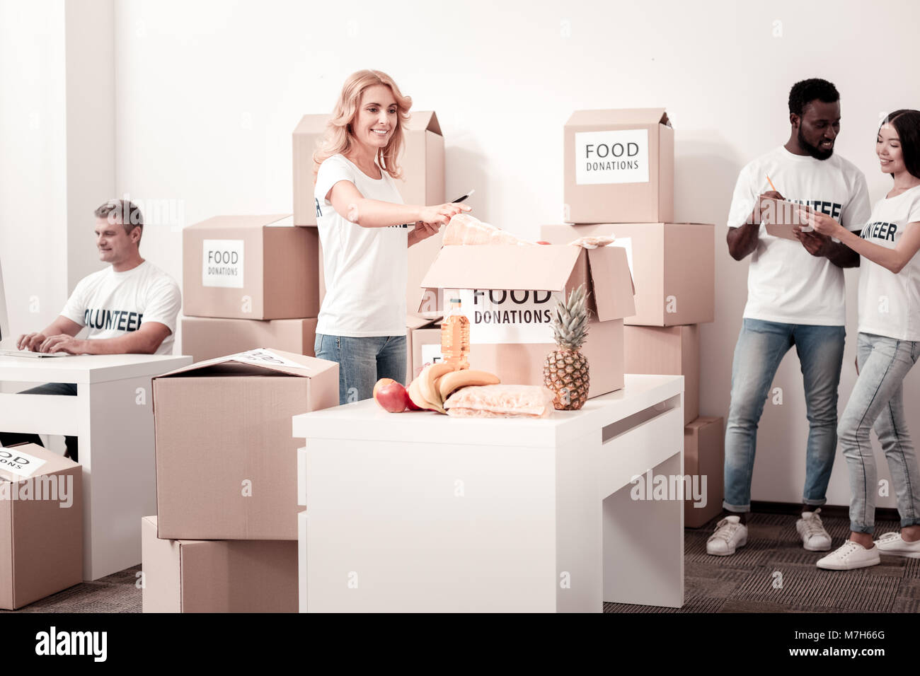 Cheerful blonde packing charity products Stock Photo - Alamy