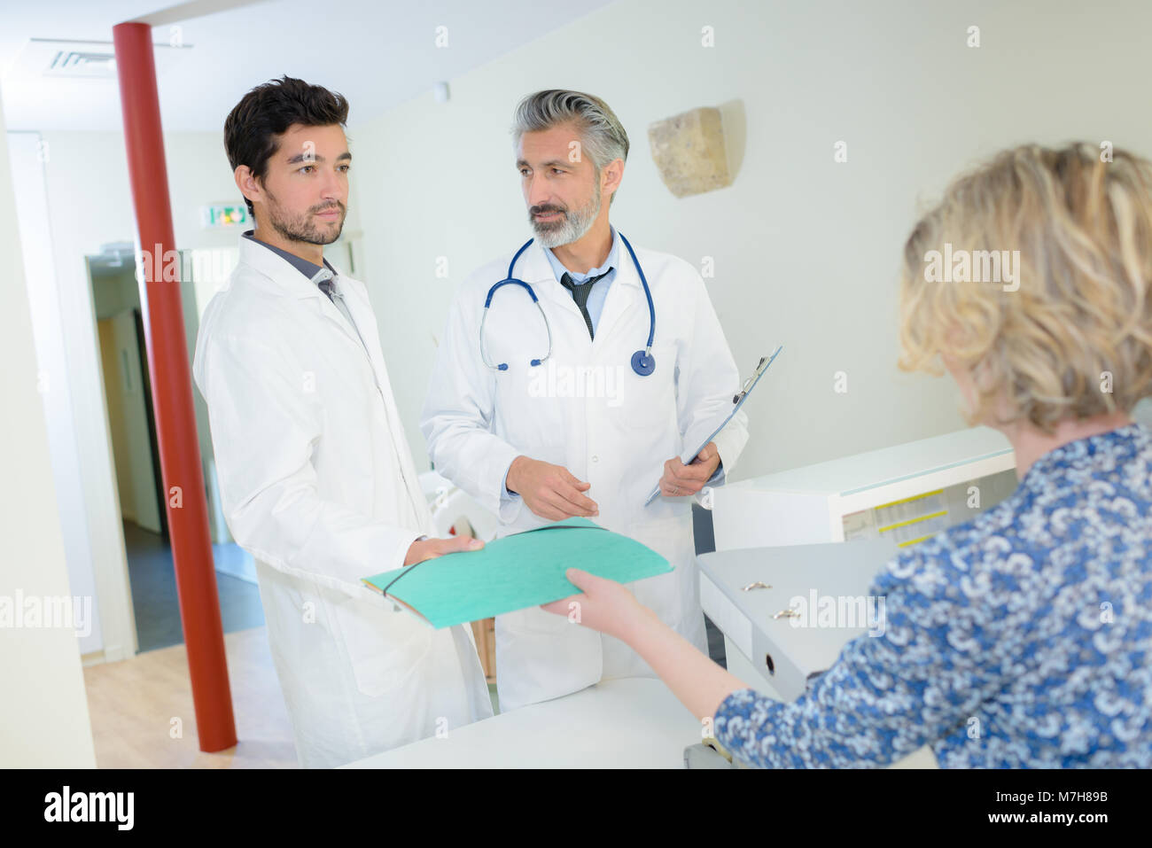 woman behind the reception desk giving folder to doctors Stock Photo ...