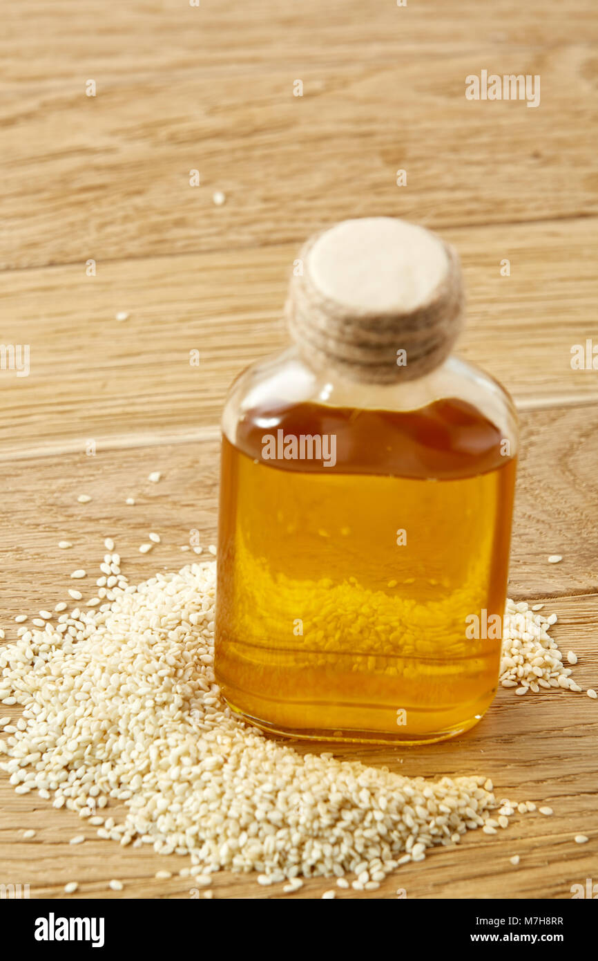 Peeled sesame seeds with oil in a small transparent glass bottle over ...
