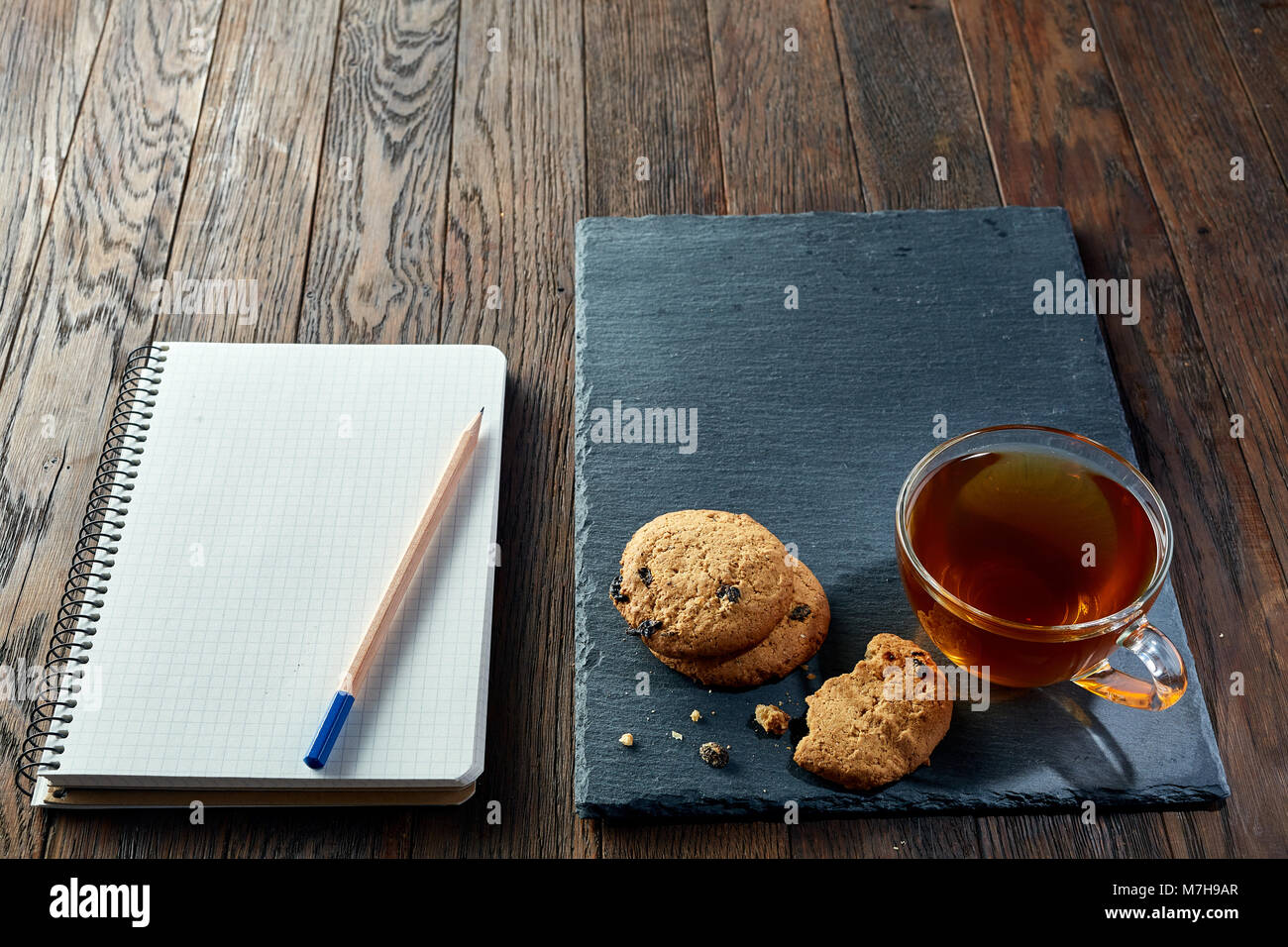 Cup of tea with chocolate chips cookies, workbook with to do list in it ...