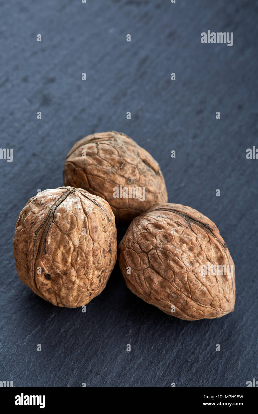 A stack of hard shells of walnuts piled together on dark background ...