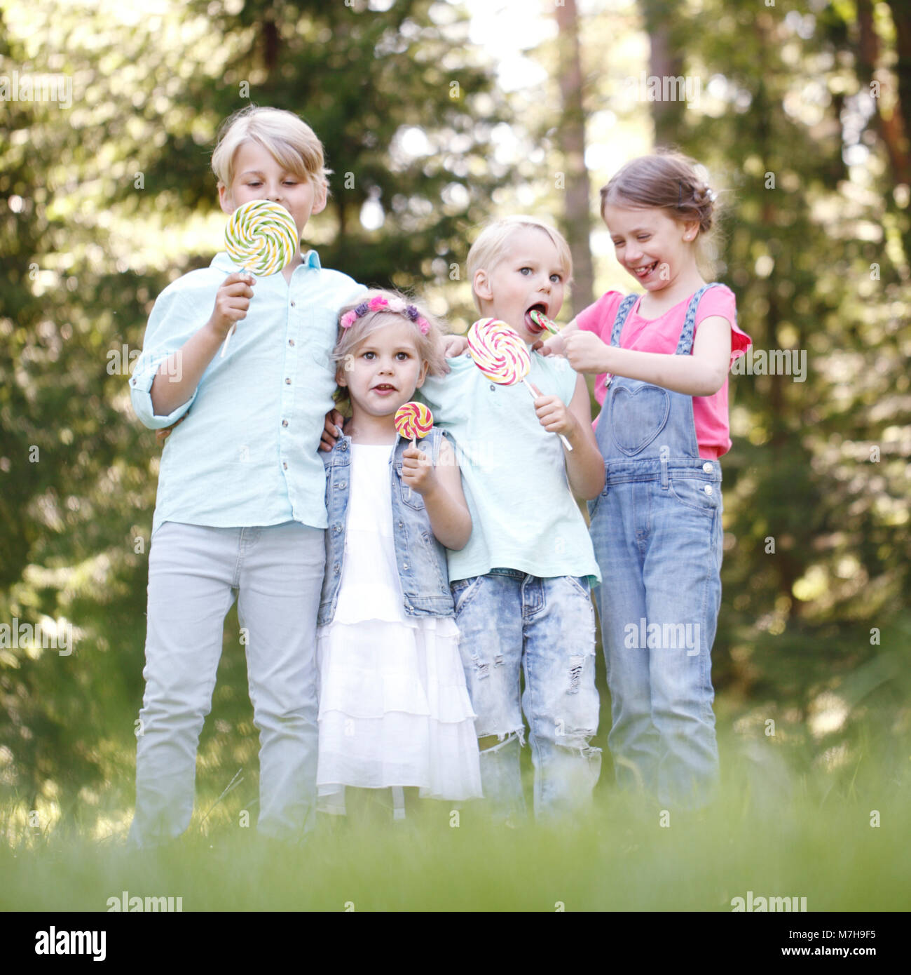 Group of happy children eating lollipops outdoors in summer park Stock ...