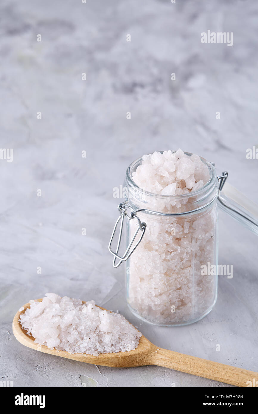 Spa concept. Bath salt pouring out of glass jar on white textured ...