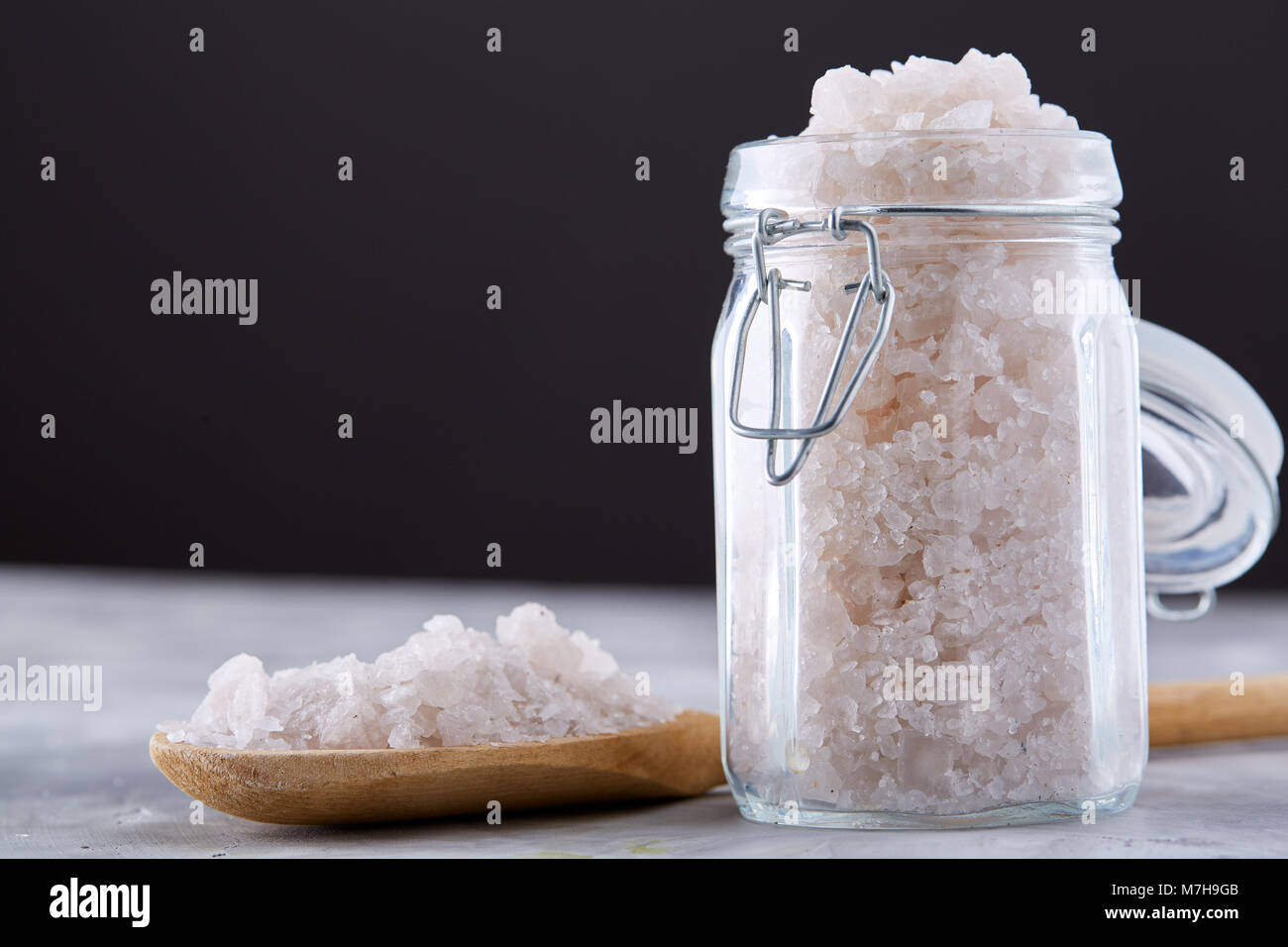 Spa concept. Bath salt pouring out of glass jar on white textured ...