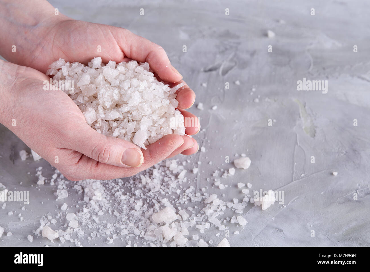 Sea salt crystals in women hand on white background, top view, close-up ...