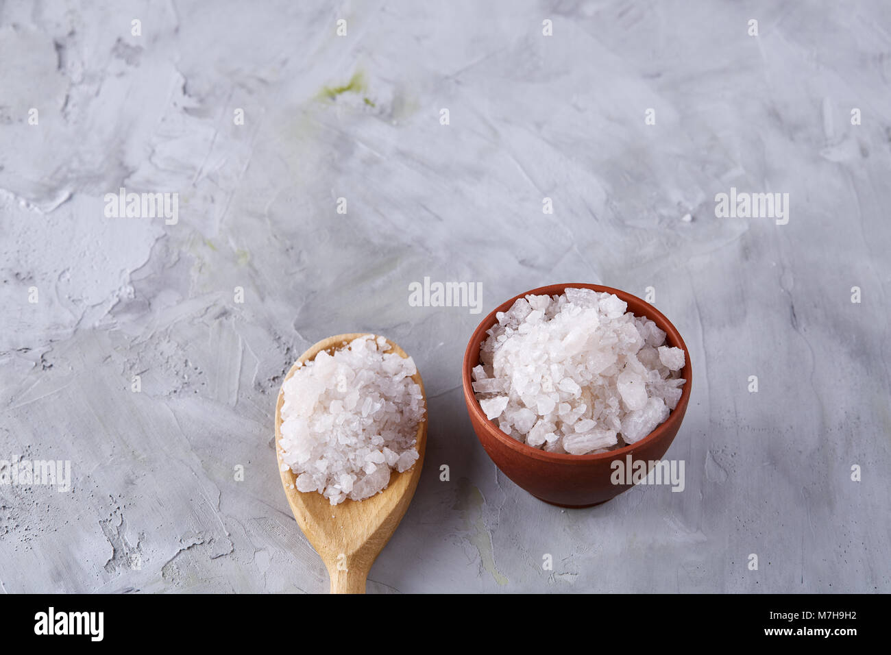 Crystal sea salt in a wooden spoon over light background, top view ...