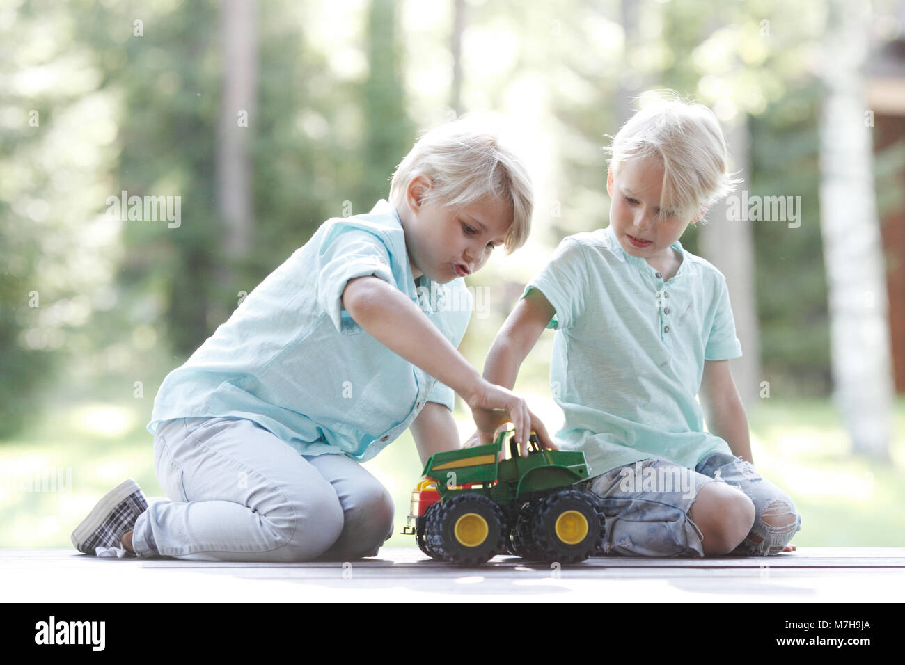 Little brothers playing with toy cars outdoors Stock Photo - Alamy