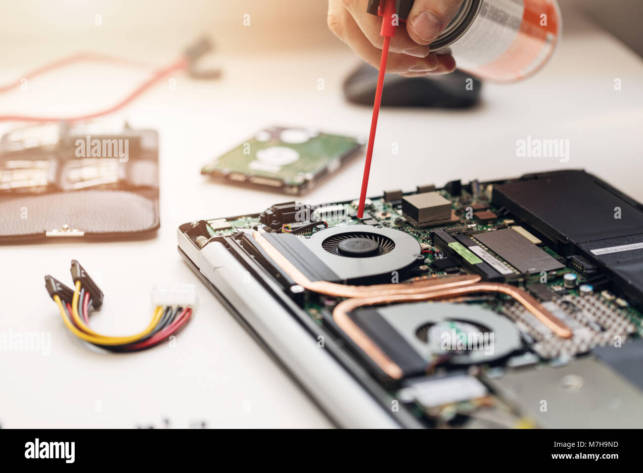 computer maintenance - closeup of technician blow out dust from laptop ...