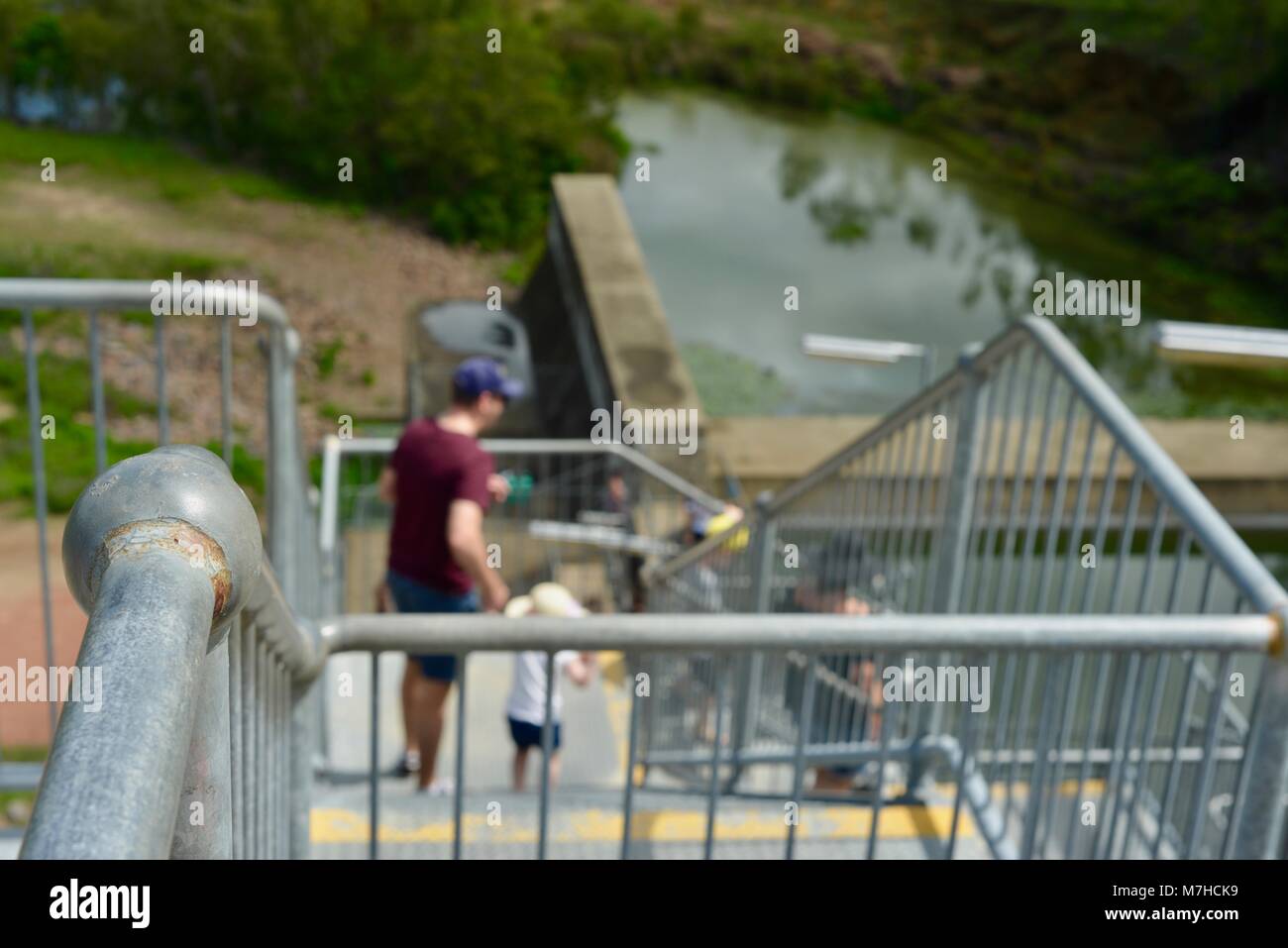 Father and son walking down galvanised steel stairs, Ross River Dam ...