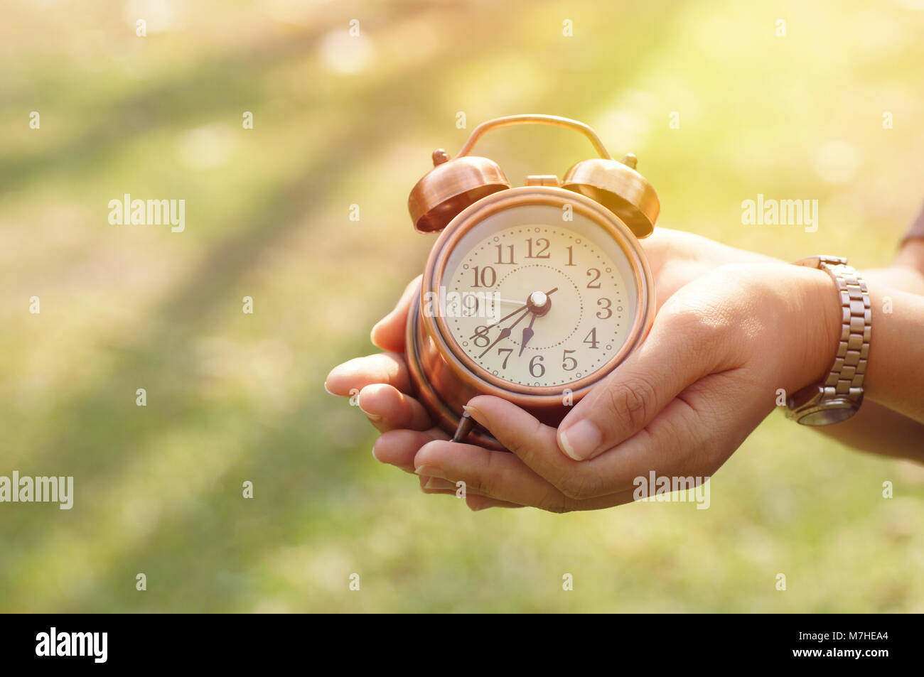 women show clock on hand in moring with space green garden background ...