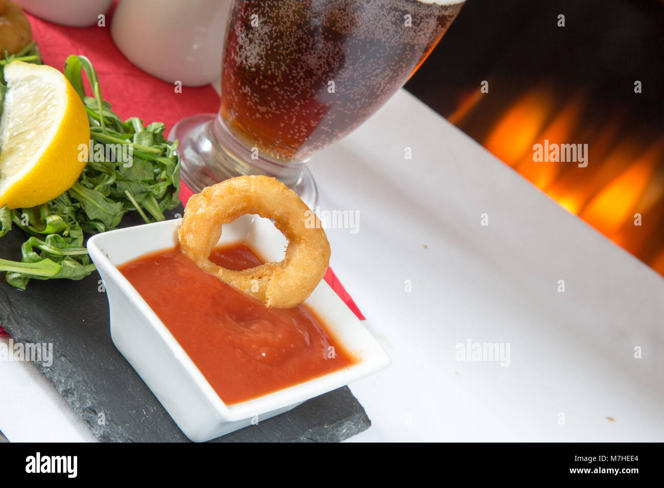 An English pub Tapas style snack of fried onion rings with Rocket salad ...