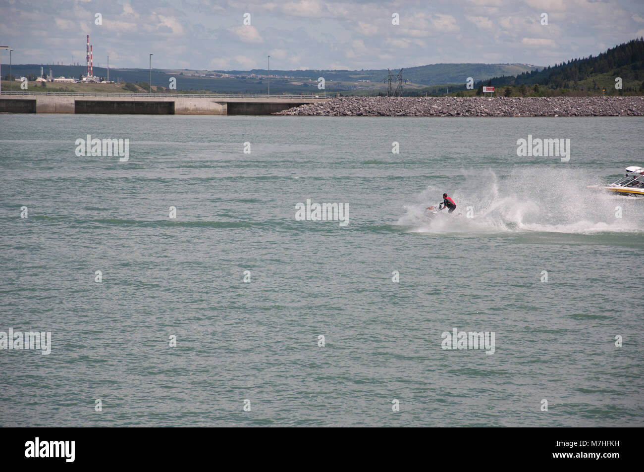 A man rides a jetski while a motorboat races him on Ghost Lake, Alberta ...
