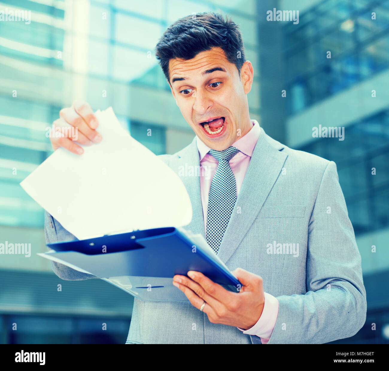 Surprised and shocked businessman reading documents on plant background ...