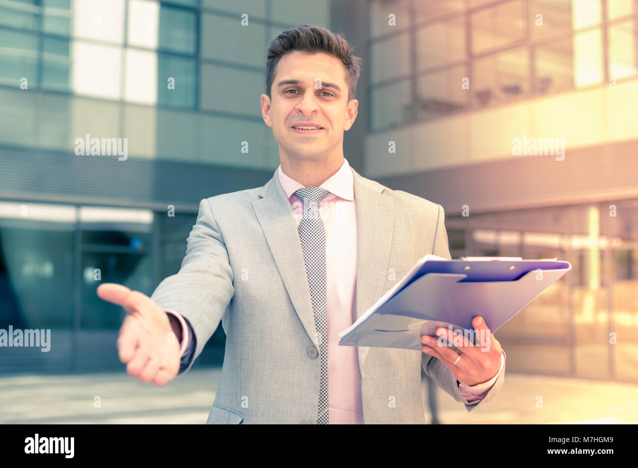 Successful businessman standing outdoor with open hand ready for ...