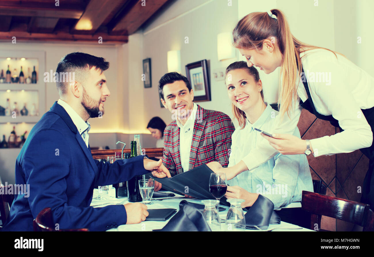 Smiling waitress taking order from guests, using digital tablet Stock ...