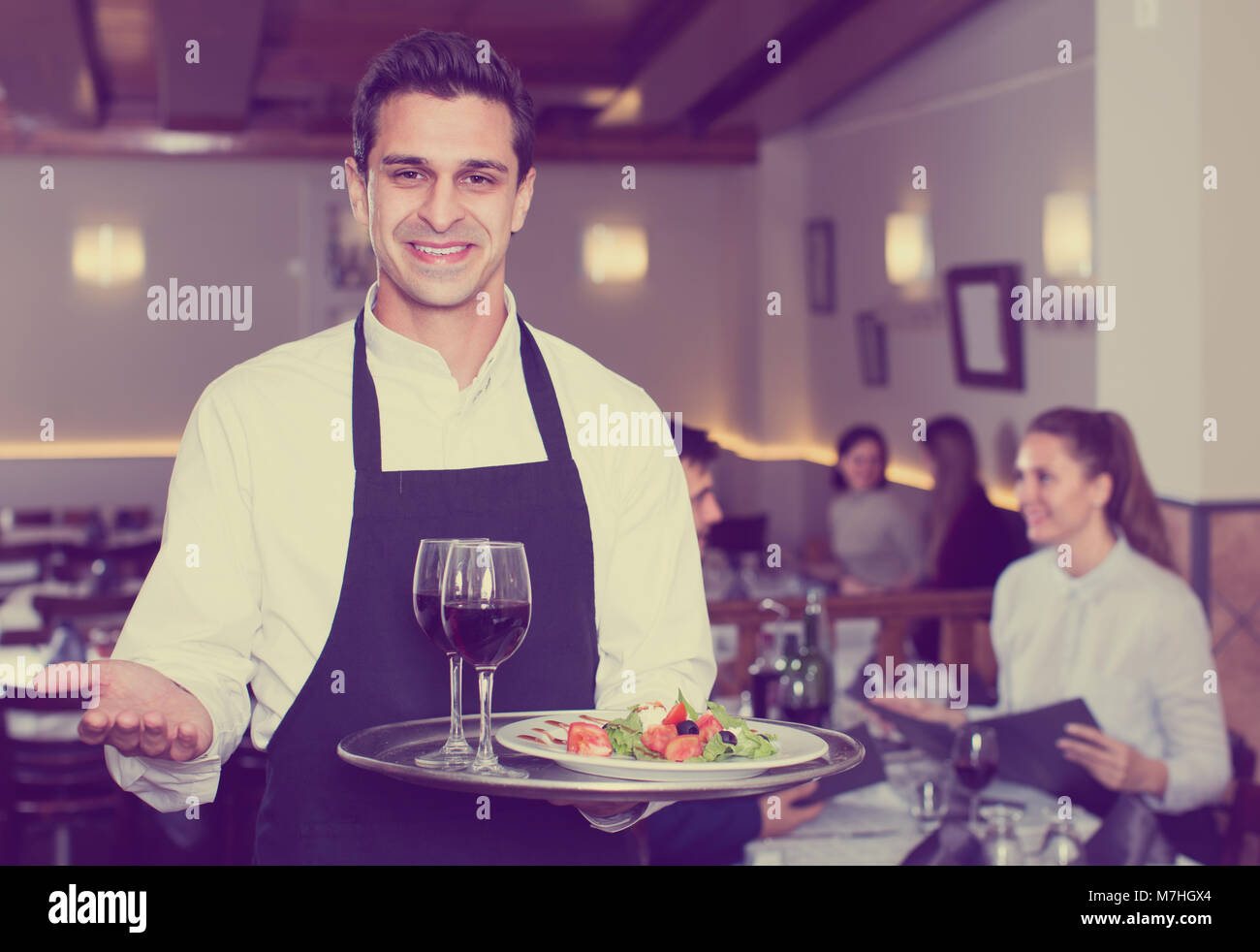 happy waiter with serving tray welcoming to cozy restaurant Stock Photo ...