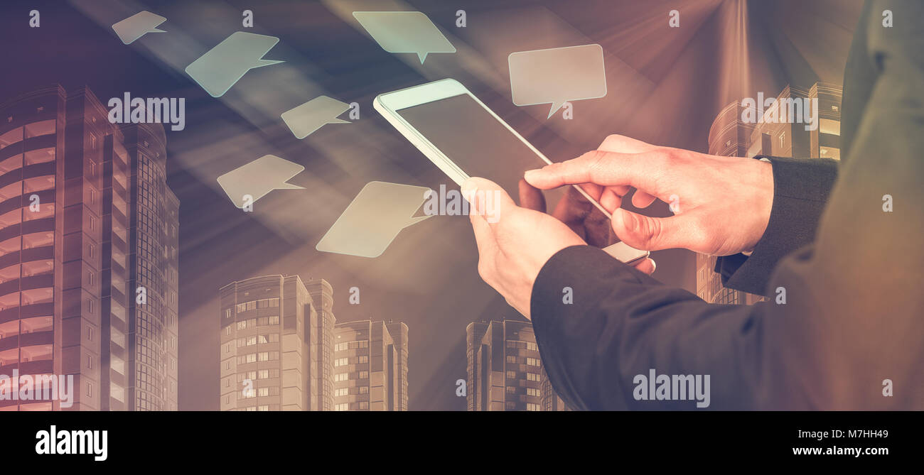 Man touching phone screen with chat icons flying around on cityscape ...