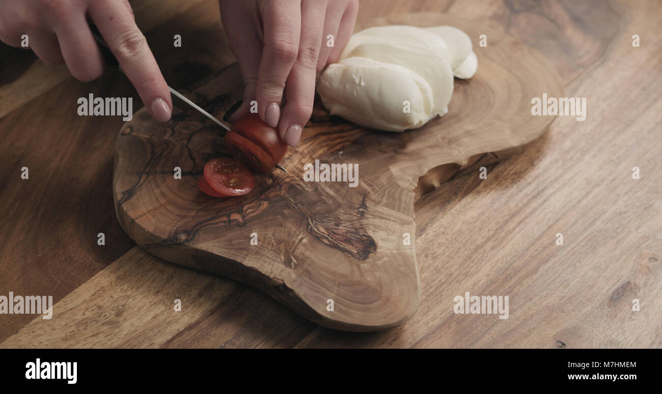 young female hands slicing cherry tomato on wooden board, wode photo ...