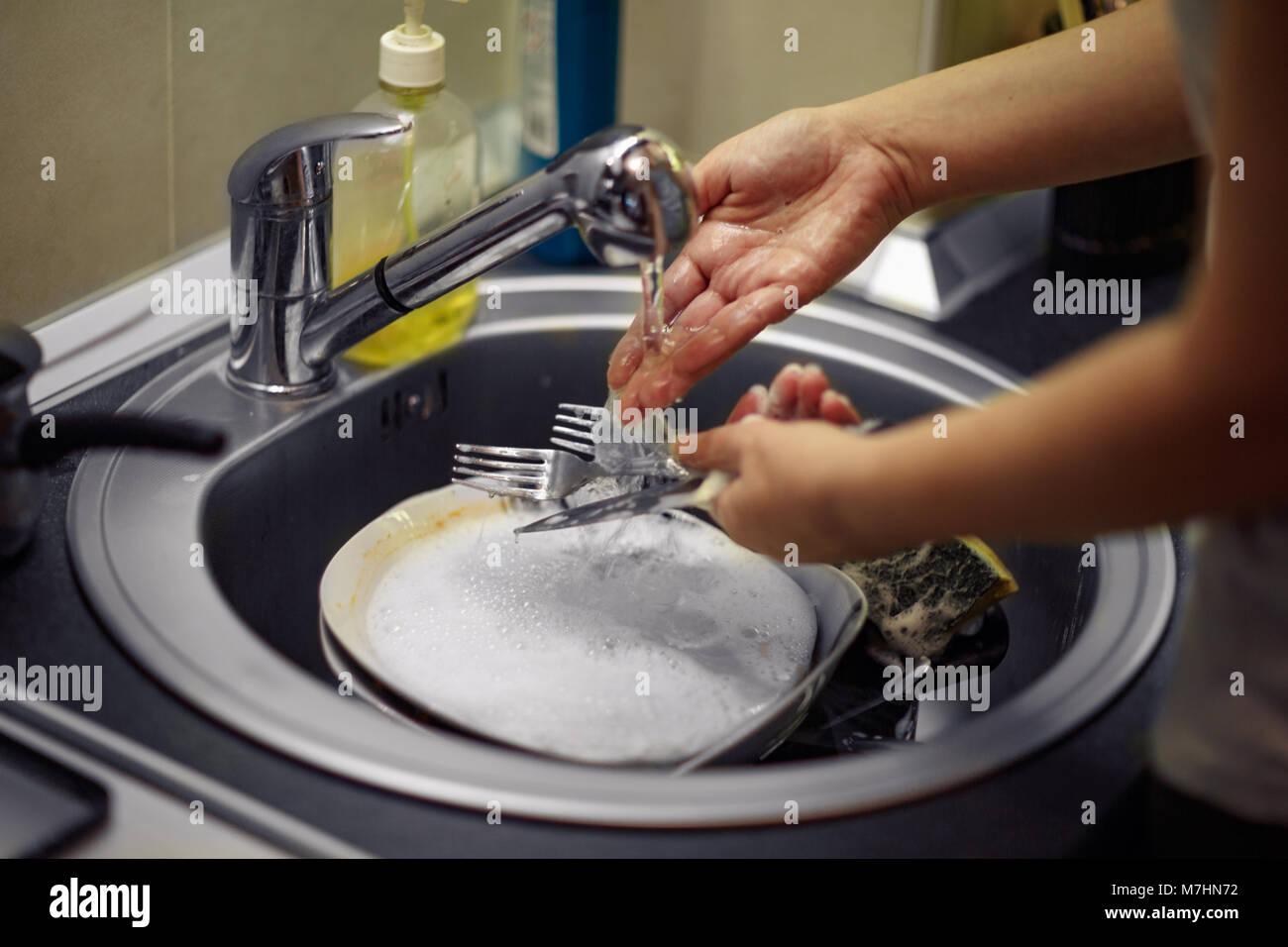 wash the dishes in the kitchen at home- close up of female hand with ...