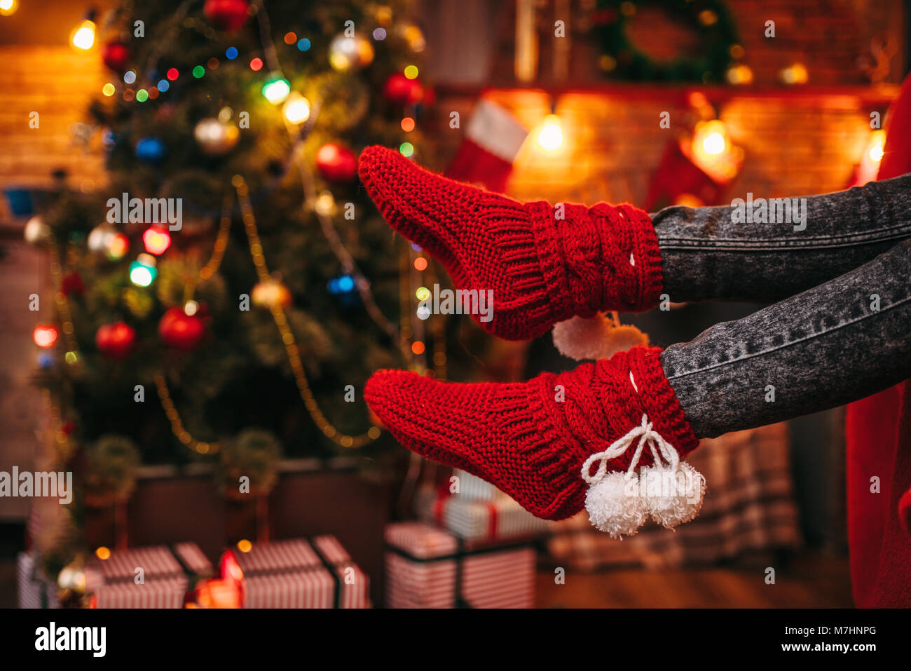 Female person feet in merry red socks, christmas tree with decoration ...