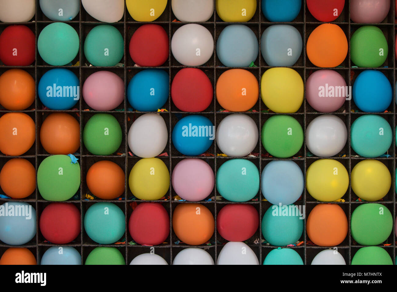 Inflated balloons waiting to be popped sit on shelves of carnival game ...