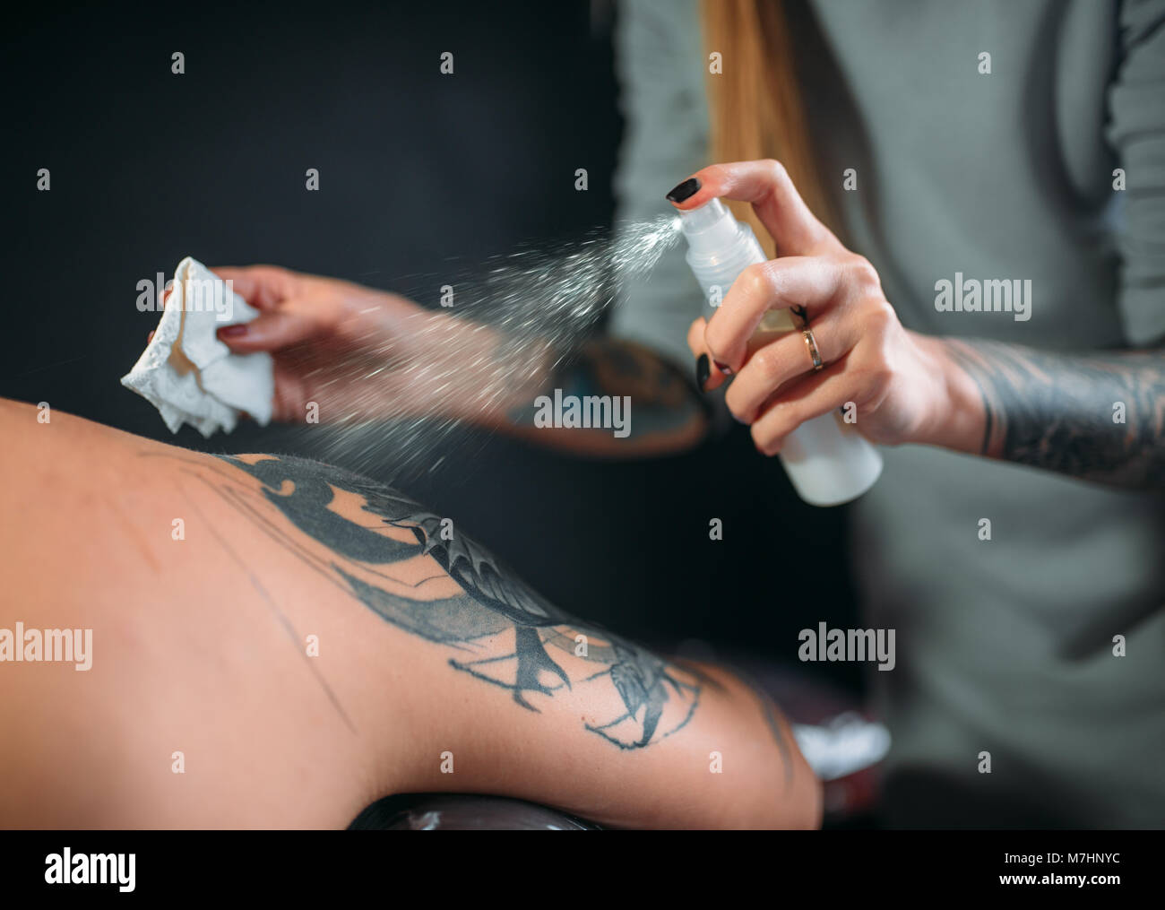 Female tattoo master sprays the freezing on clients skin, professional ...