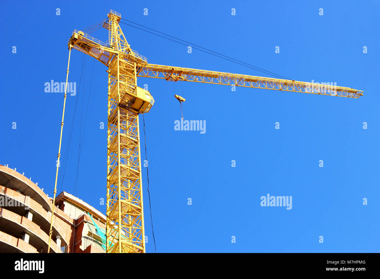 High-rise construction crane near the house under construction on a ...