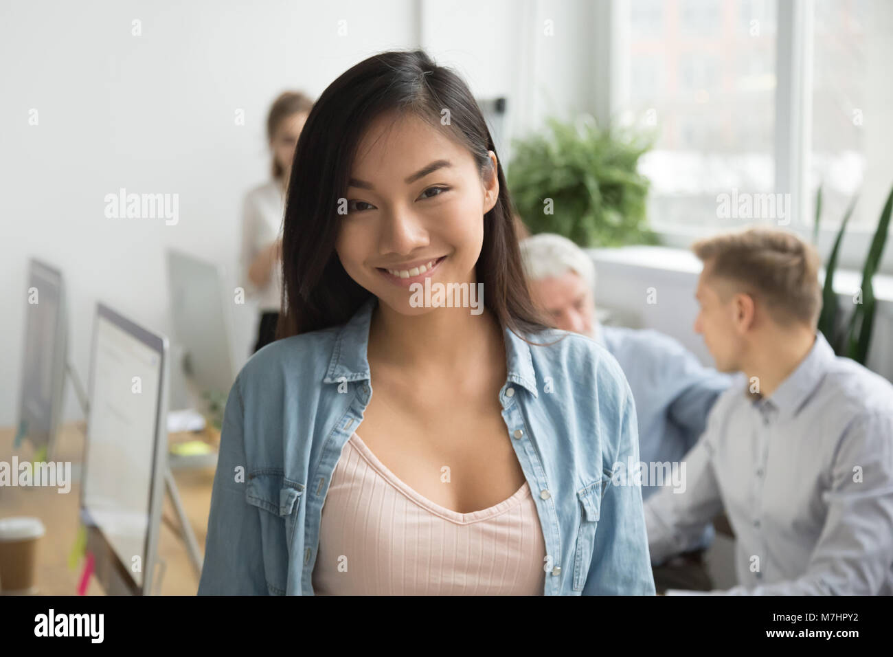 Smiling asian office employee looking at camera working with col Stock ...