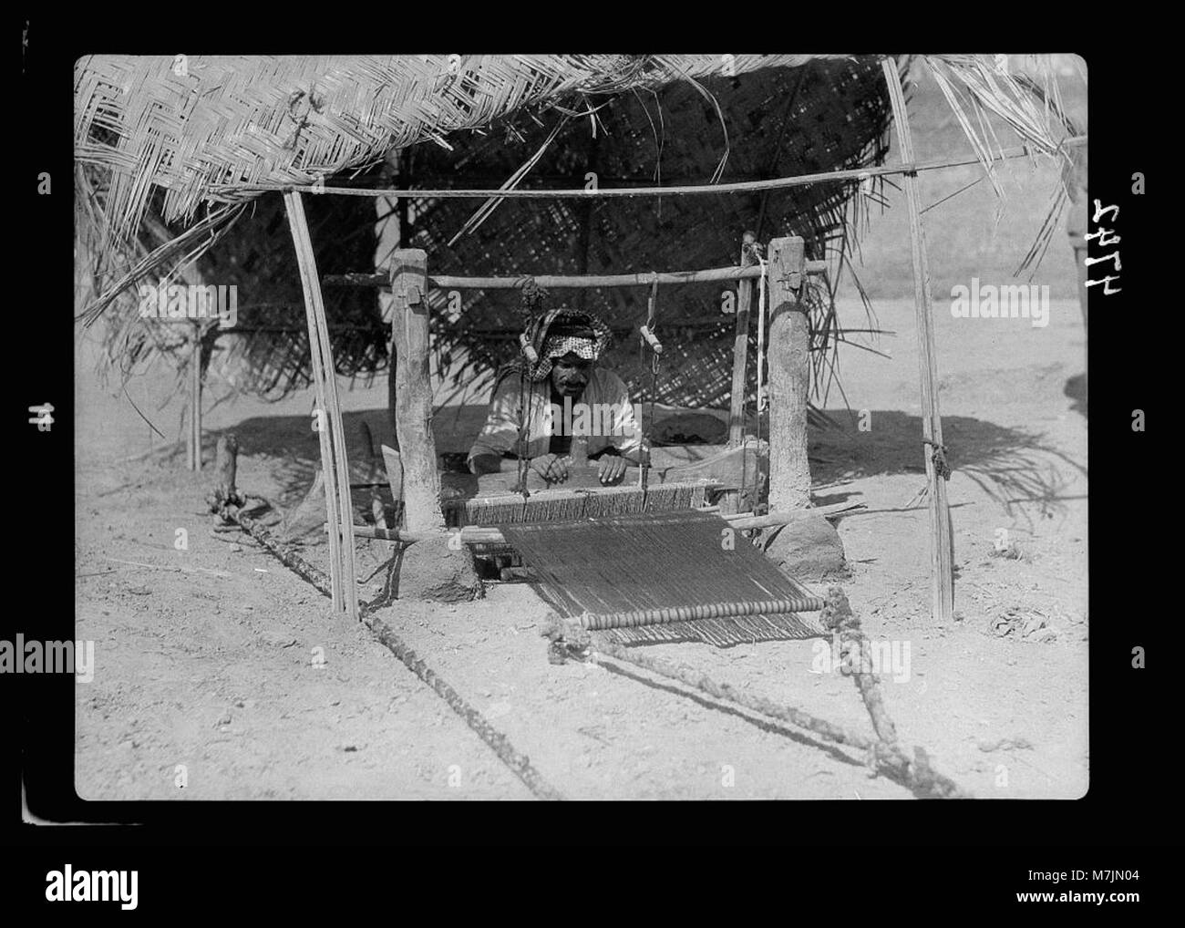 This image depicts a Muslim villager in Kifl, Iraq, working on his loom ...