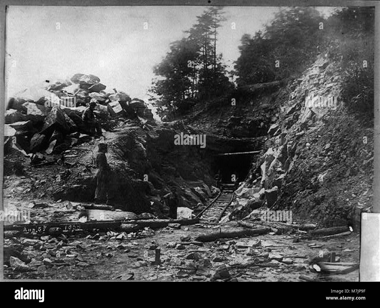 A photograph showing a track leading into a tunnel cut through rock ...