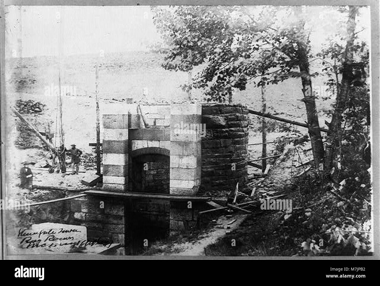 The image shows two men standing near a tower, possibly a historical ...
