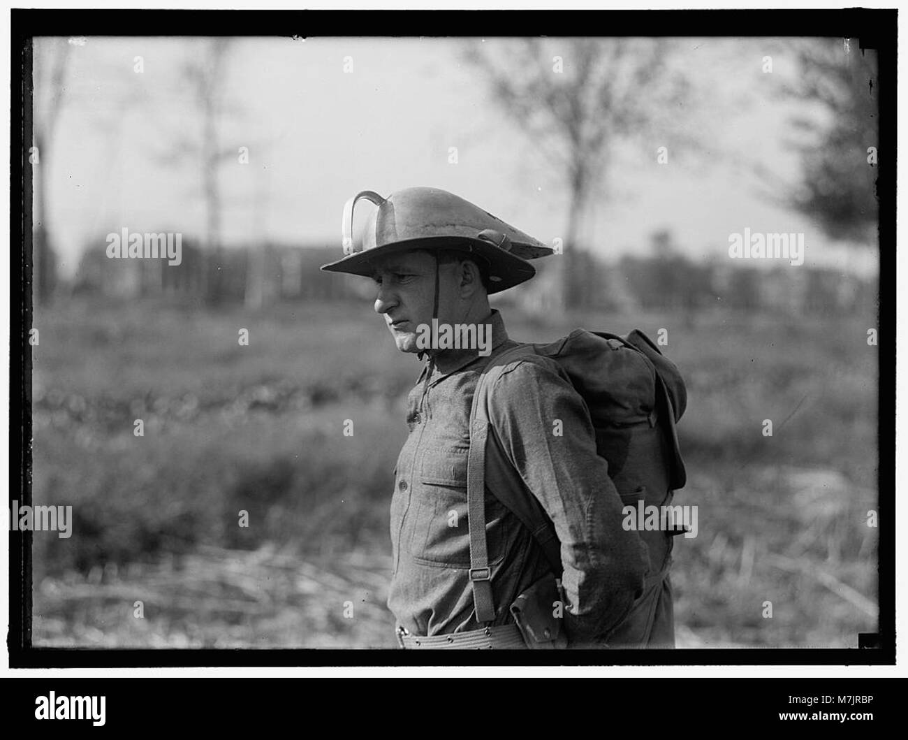 This image shows Leonard D. Mahon with a steel helmet he invented ...
