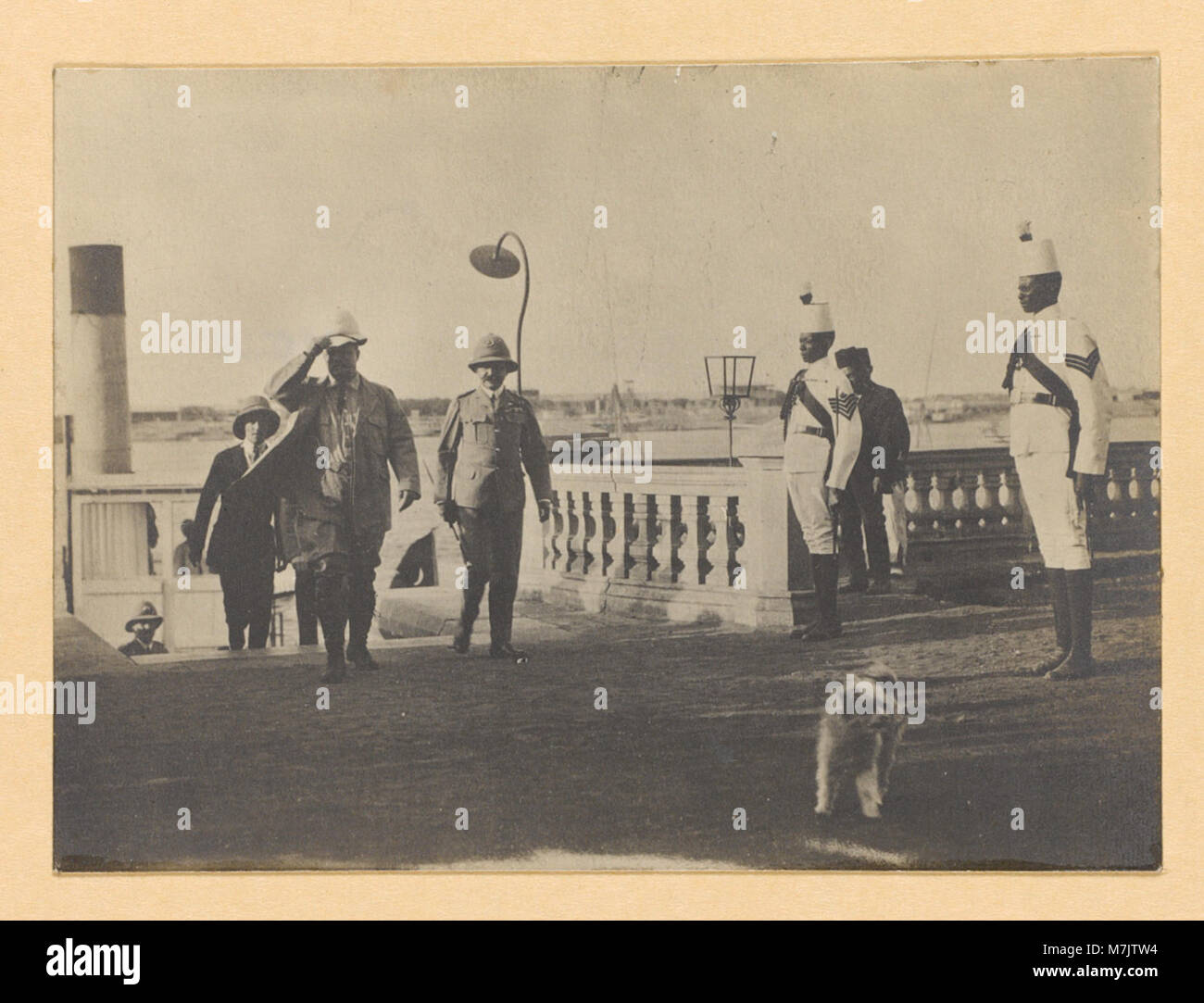 A photograph of Theodore Roosevelt, accompanied by others, walking away ...