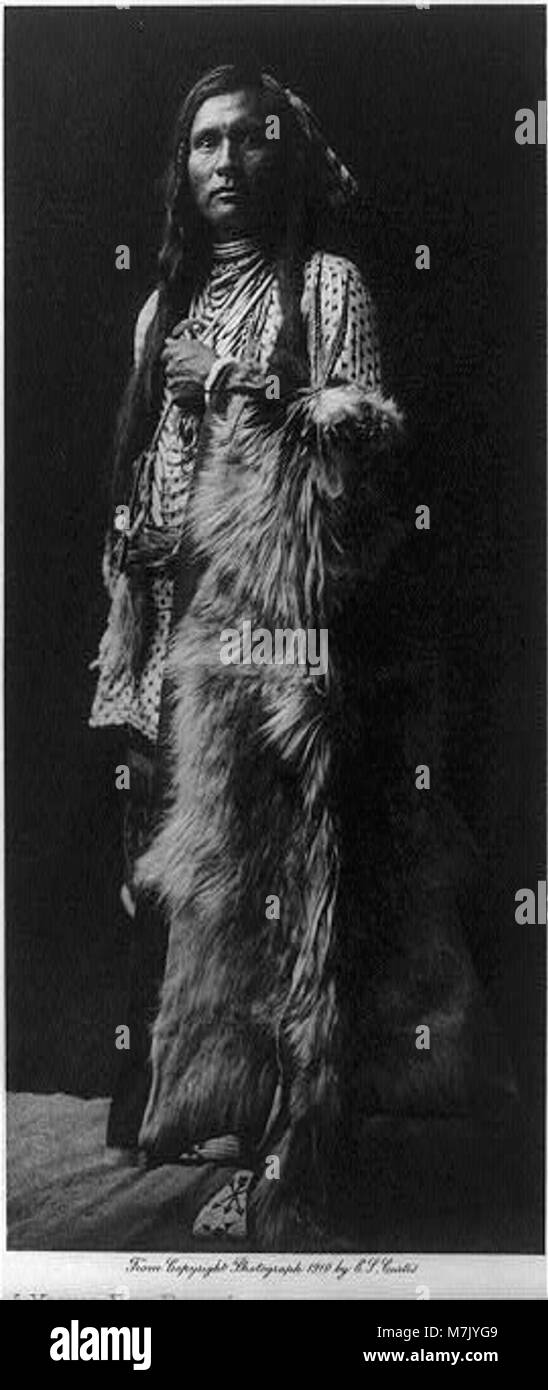 A historical photograph of a young member of the Nez Perce tribe, depicting traditional clothing ...