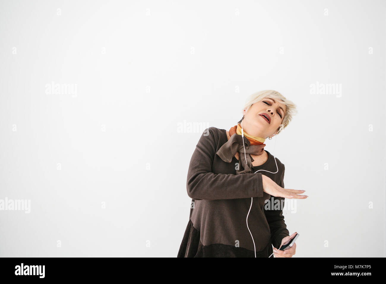A positive elderly woman listens to music, dances and sings. The older ...