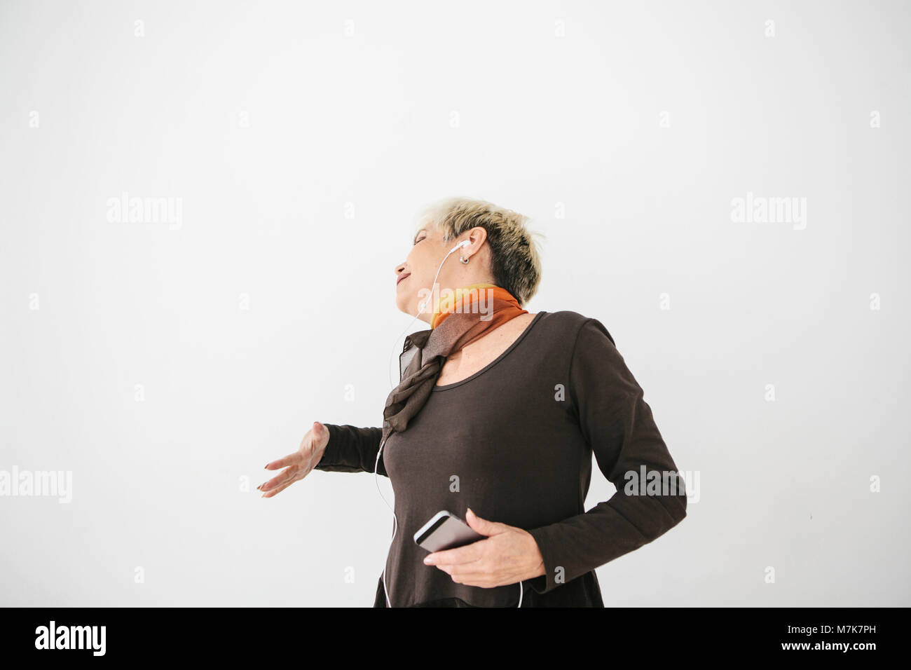A positive elderly woman listens to music, dances and sings. The older ...