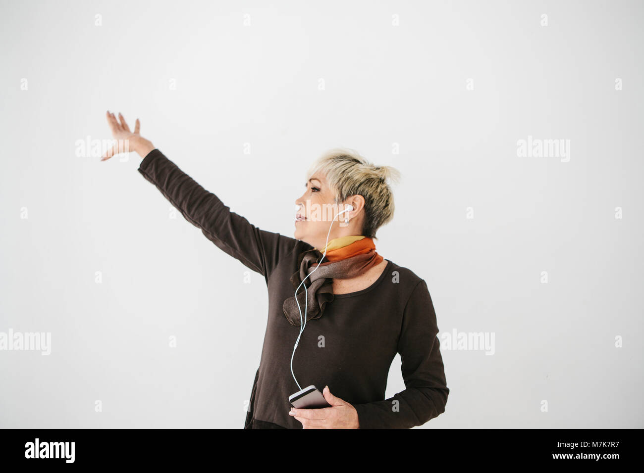 A positive elderly woman listens to music, dances and sings. The older ...