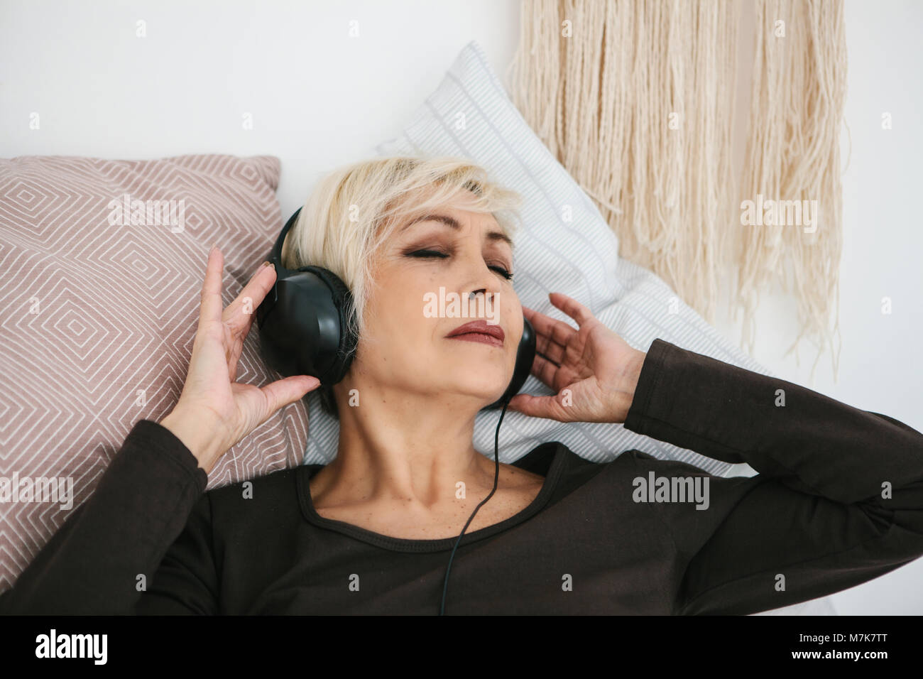 Positive elderly woman listening to music. The older generation and new ...