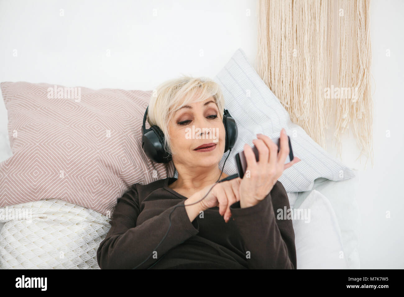 Positive elderly woman listening to music. The older generation and new ...