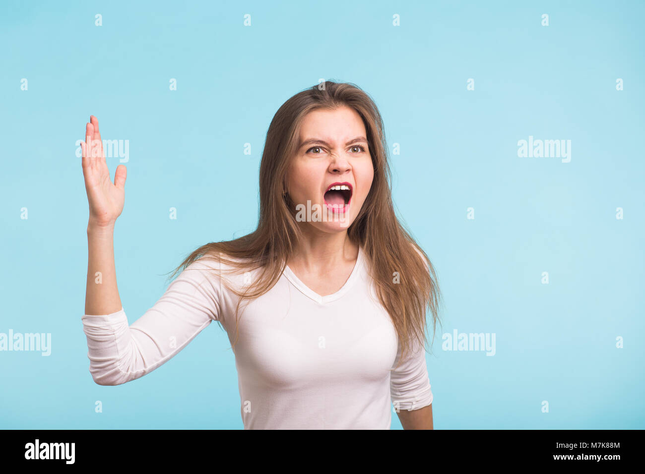 Angry aggressive woman with ferocious expression on blue background ...