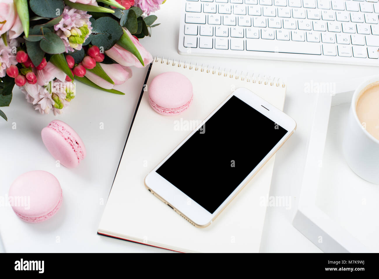 Lady bloggers work desk with pink flowers and macaron cakes on white ...